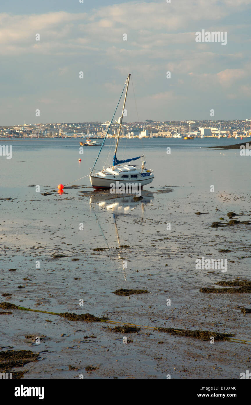 Small dingy at low tide with the industrial view of Devonport Dockyard ...