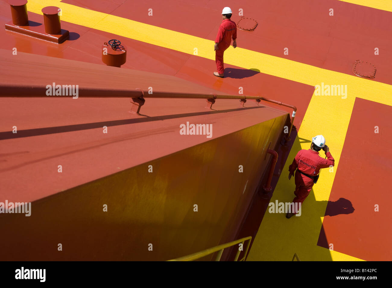 Workers walking on yellow safe route markings on a FPSO. Anoa ...