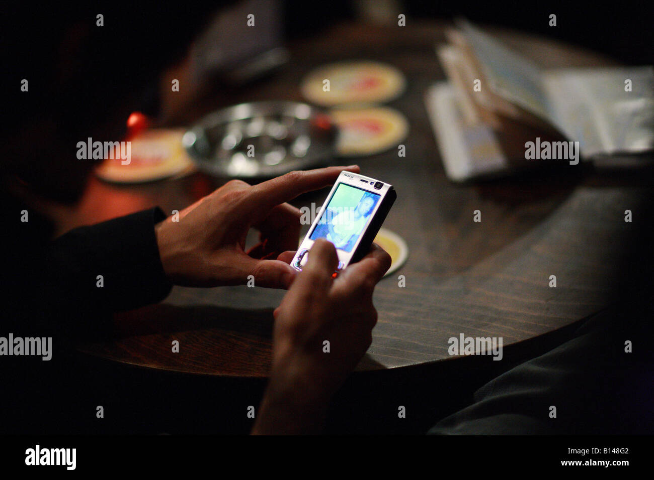 A customer in a pub,emailing using his wireless communication device ...