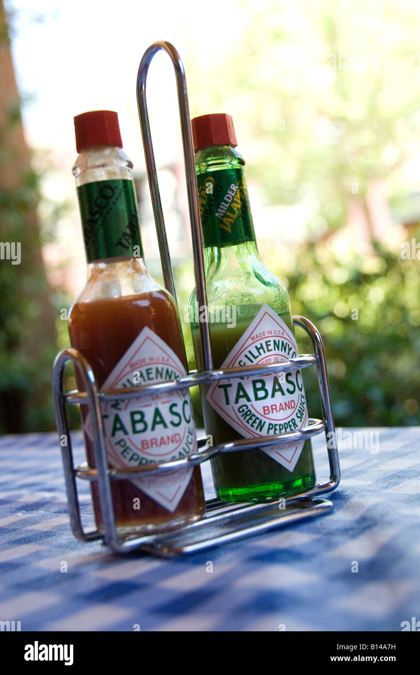 Bottles of tabasco sauce in holder on table Stock Photo - Alamy