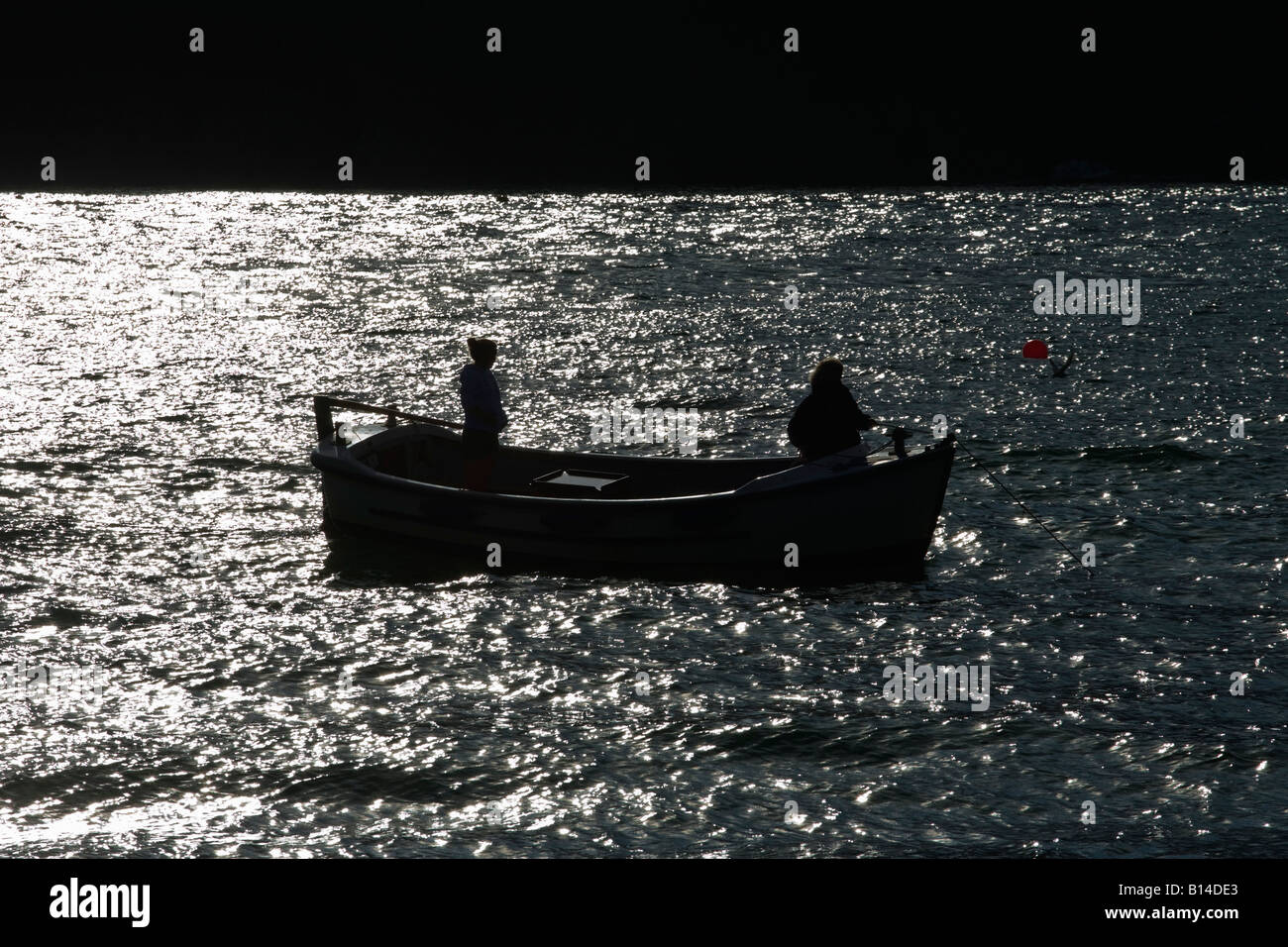 Mill Bay, Salcombe, Devon. Boat in the estuary with sailors, silhouette ...