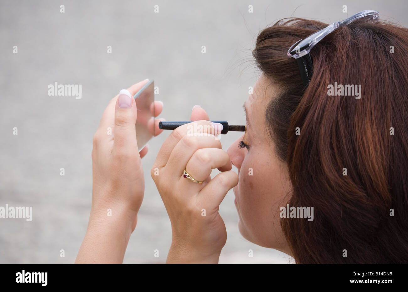 Europe Attractive young woman using hand held mirror applying eye face ...