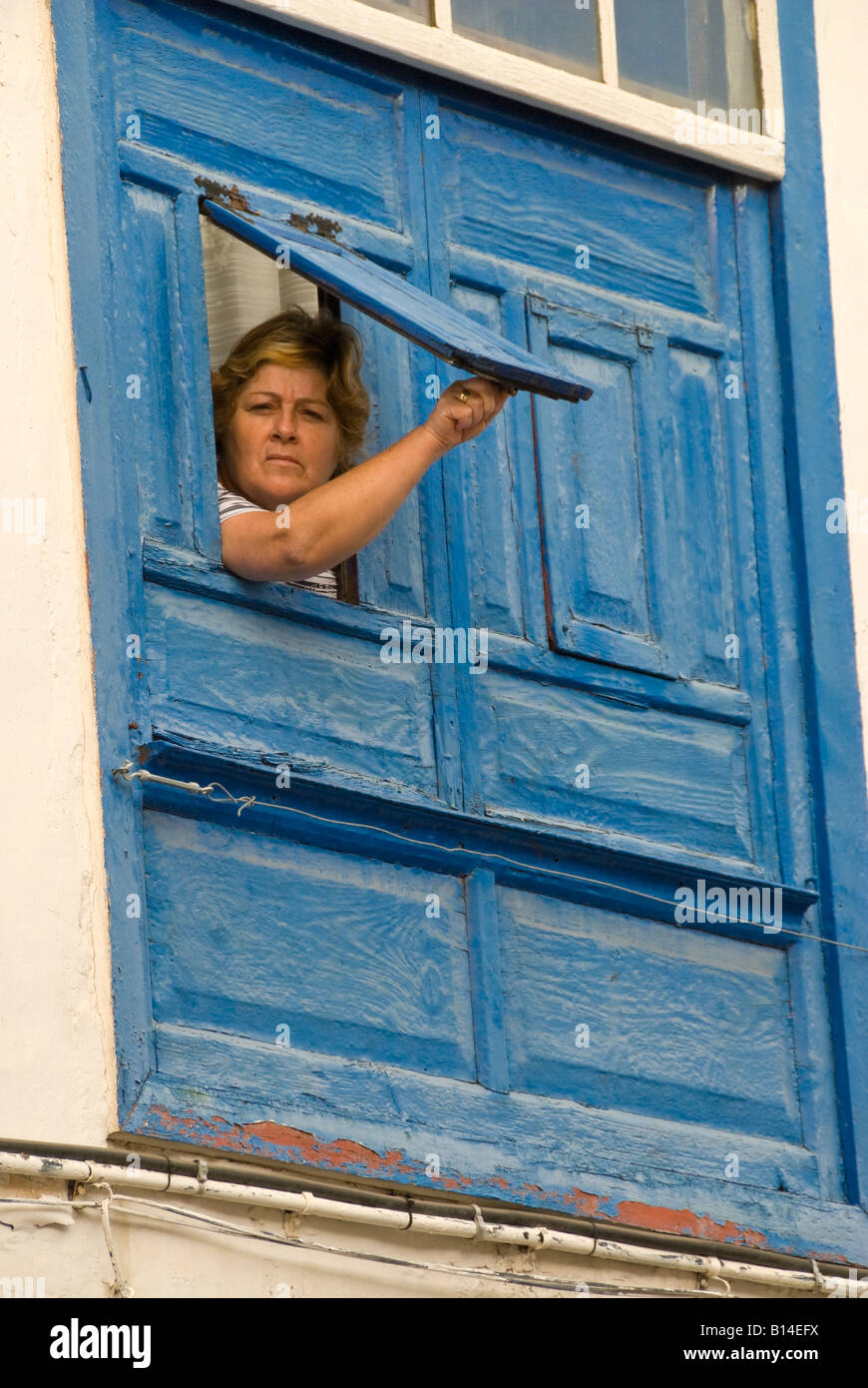 Woman looking out of a shuttered window San Sebastian La Gomera Canary ...