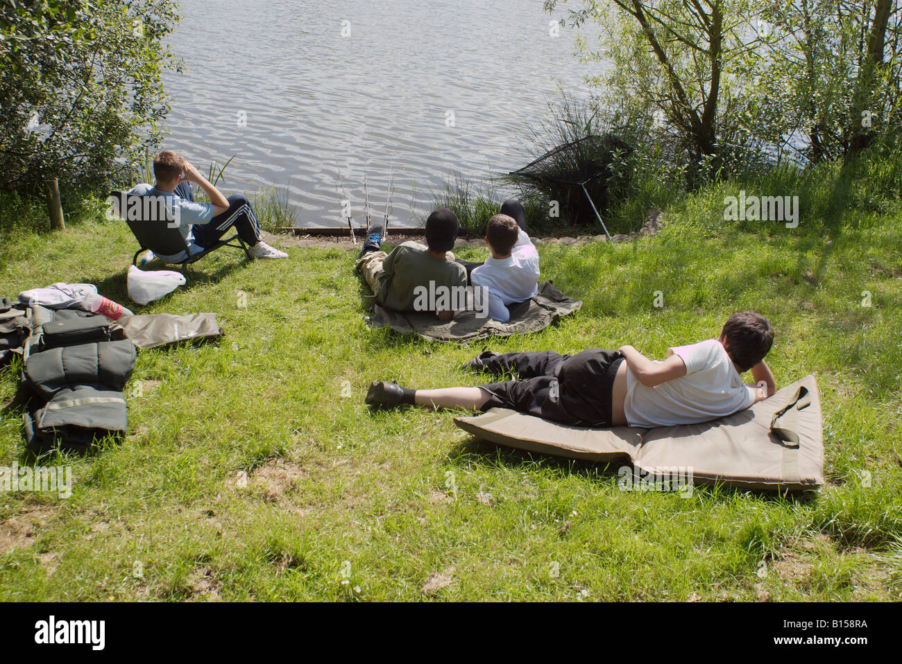 Four teenage boys lying beside Goldsworth Park lake Woking Surrey ...