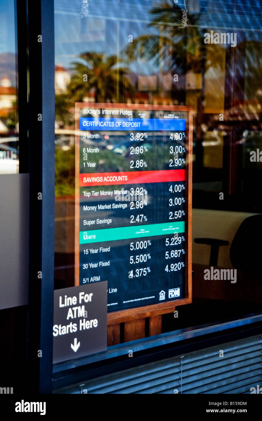 Palm trees are reflected in a store front bank window s display of ...