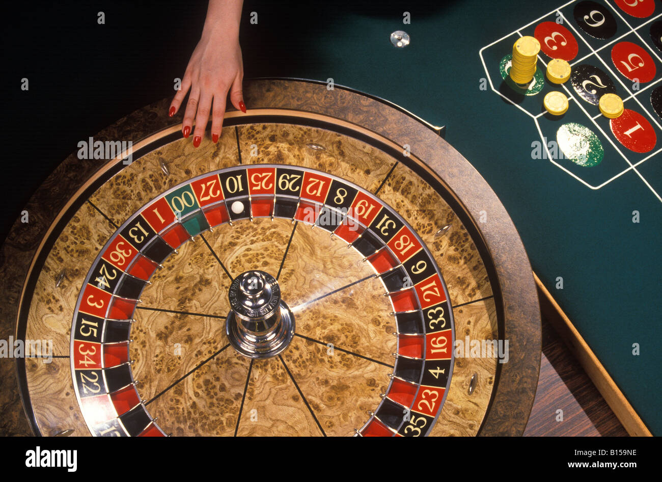 A female hand with red finger nails spins the roulette wheel in a ...