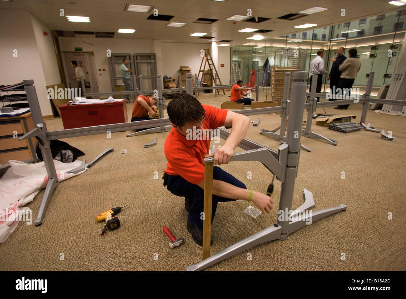 A team of workmen construct the frame of a desk in a newly constructed ...