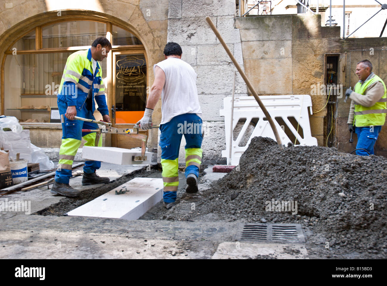 Construction workers carrying a slab of stone to be placed in a ...