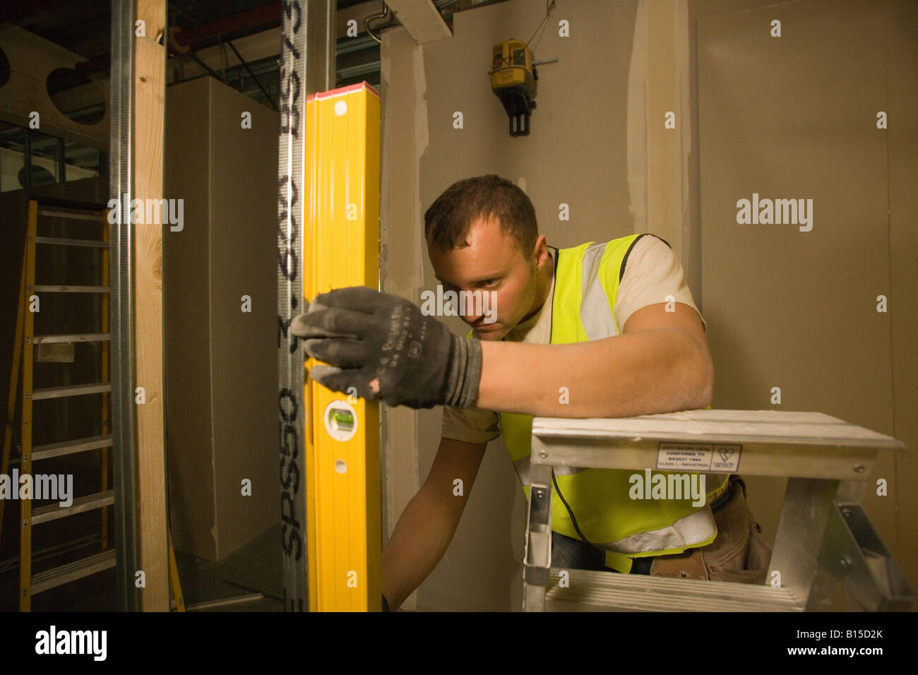 A workman holds a spirit level to check the alignment of a fitting ...