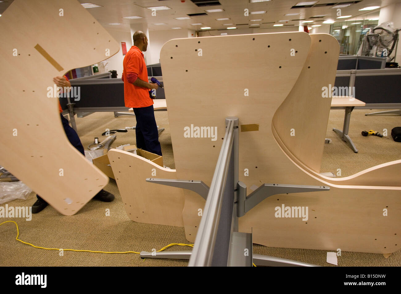 Workmen construct large communal desks in a newly constructed office ...