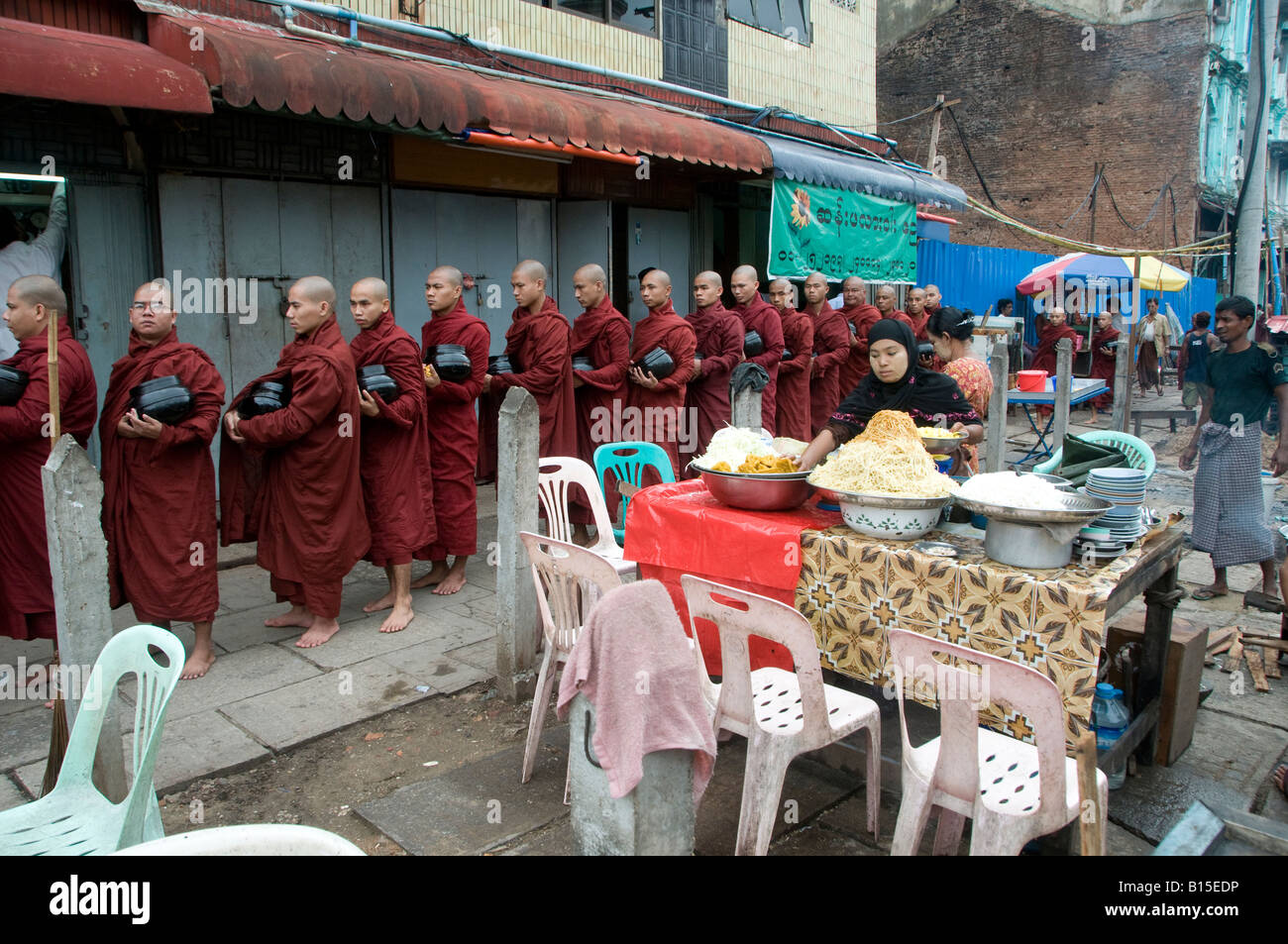 Buddhist monks pass a food stall on their way to their morning alms ...