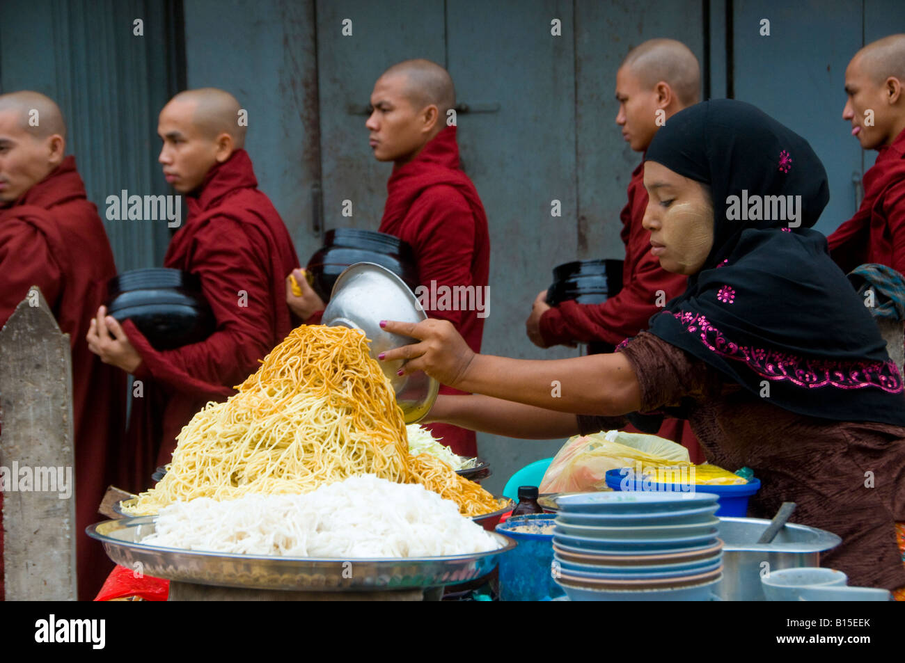 Buddhist monks pass a food stall on their way to their morning alms ...