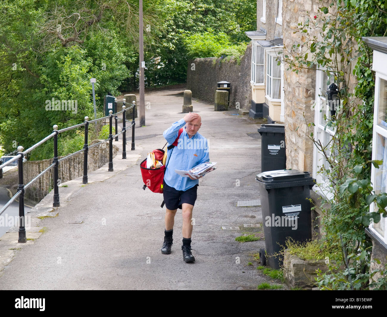 Postman in summer uniform delivering mail in a steep old fashioned ...
