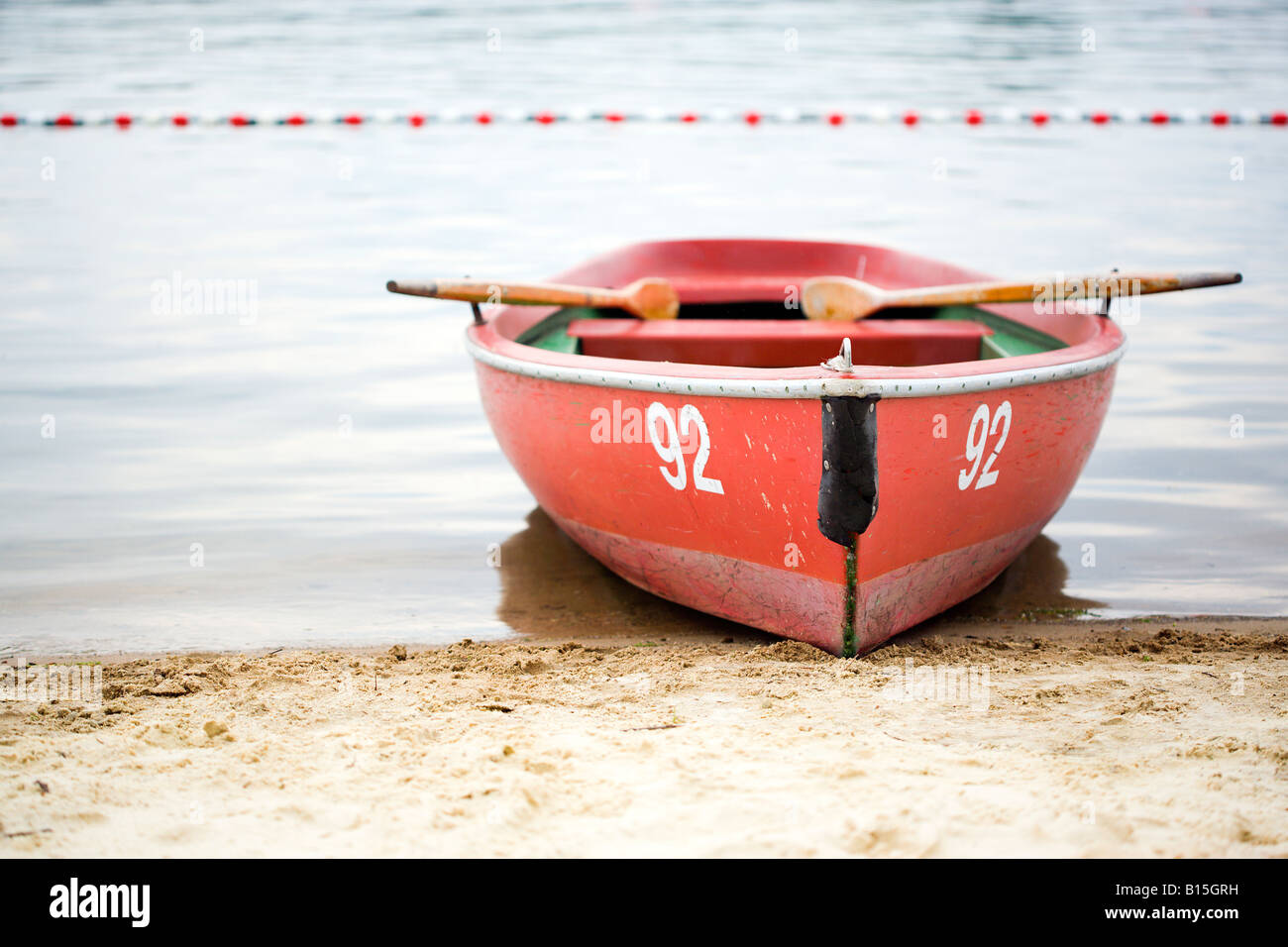 red rowing boat at beach of lake, no-swimming-line in background Stock ...