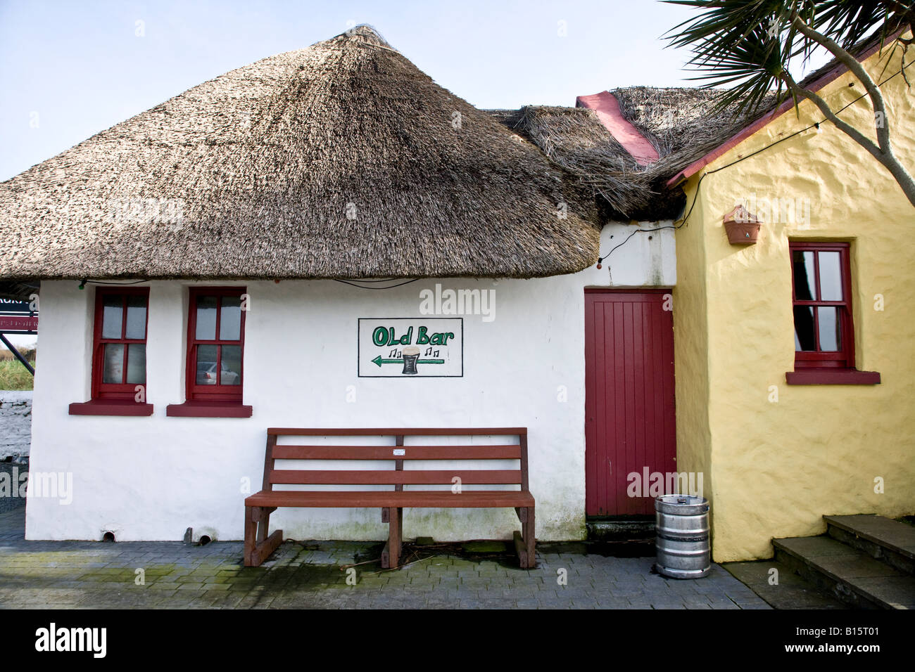 Exterior of a cottage with thatched roof and old bar sign, County Clare ...