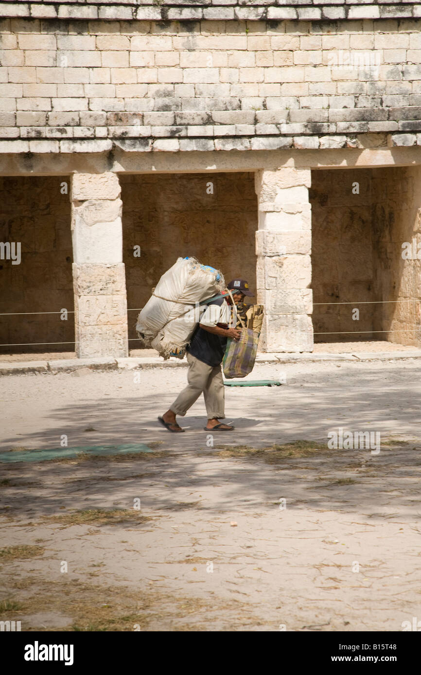 A trader carries his wares in front of an ancient Mayan temples at ...