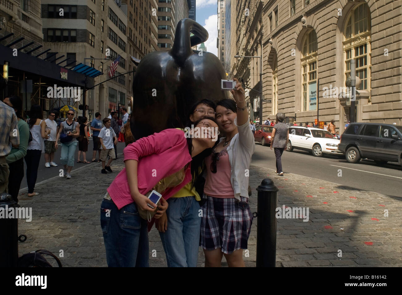 Tourists pose for photos in front of the Wall Street Bull on Broadway ...