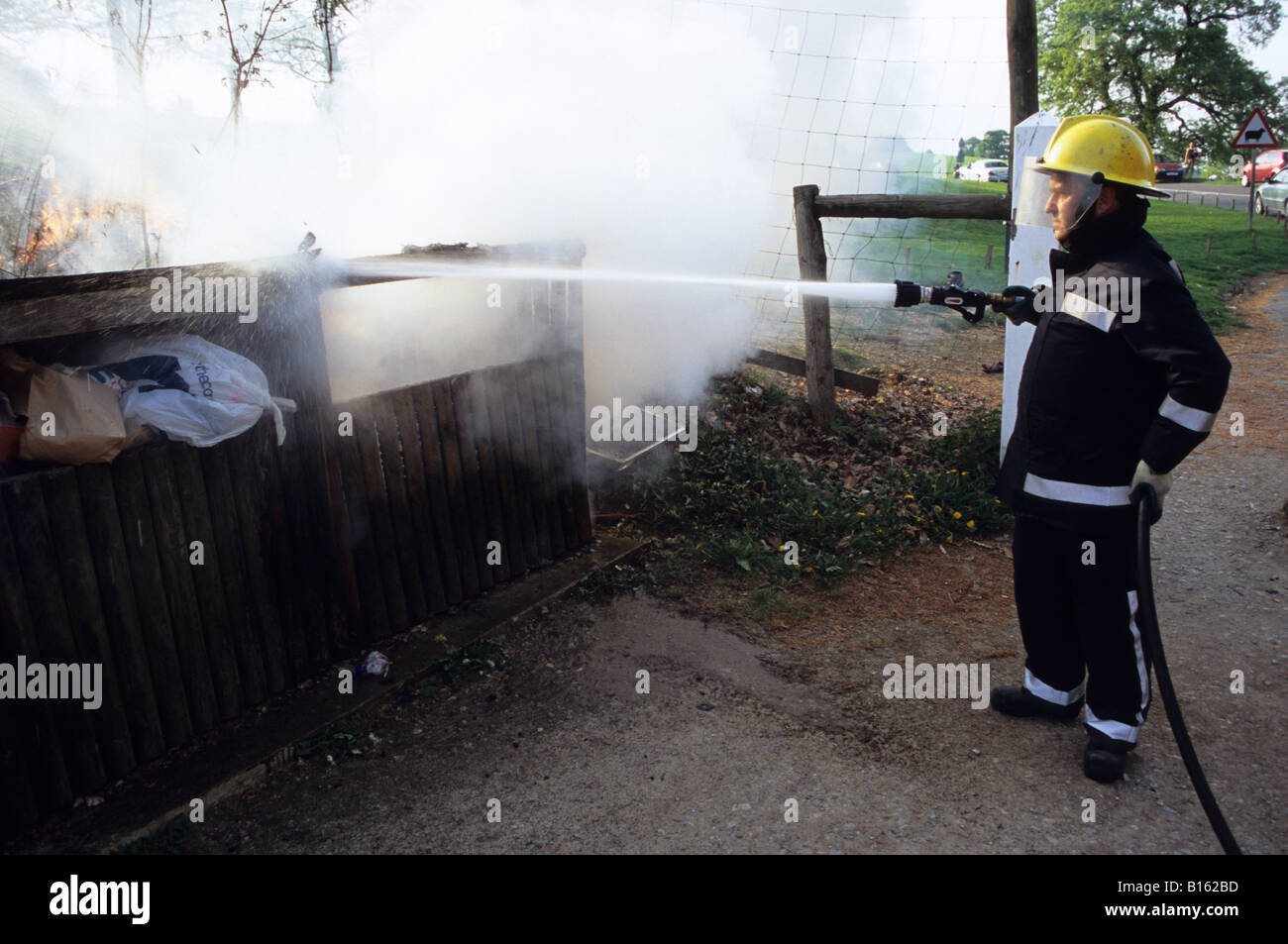 Fire Fighter Extinguishing A Fire In A Litter Bin Stock Photo - Alamy