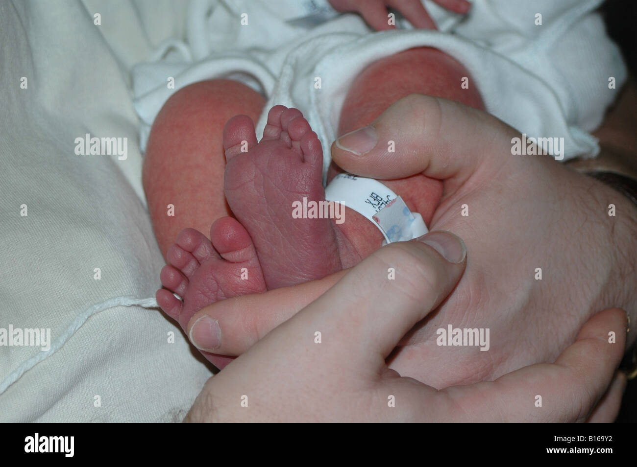A mom is holding the tiny red feet of her newborn baby girl Stock Photo ...