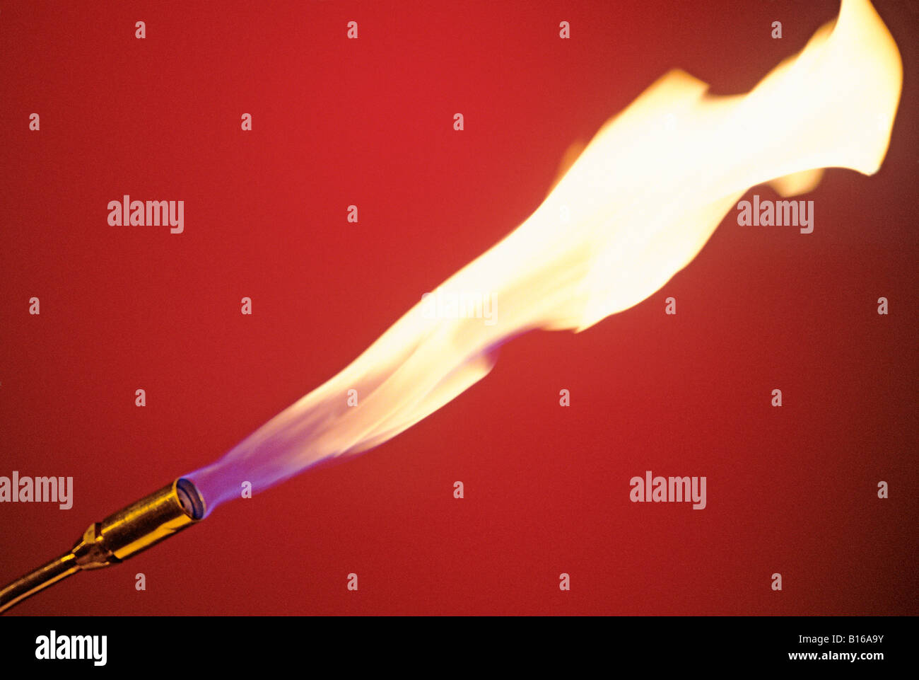 Long flame of propane torch against red background Stock Photo - Alamy
