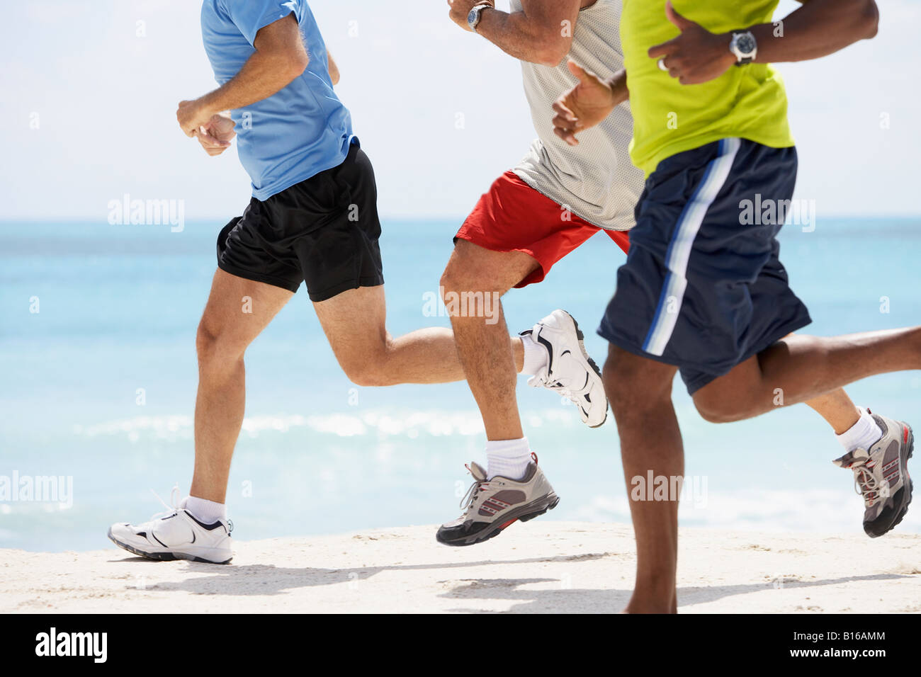 Multi-ethnic men running in beach Stock Photo - Alamy