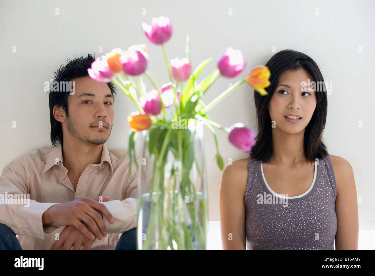 Asian couple looking at flowers in vase Stock Photo - Alamy