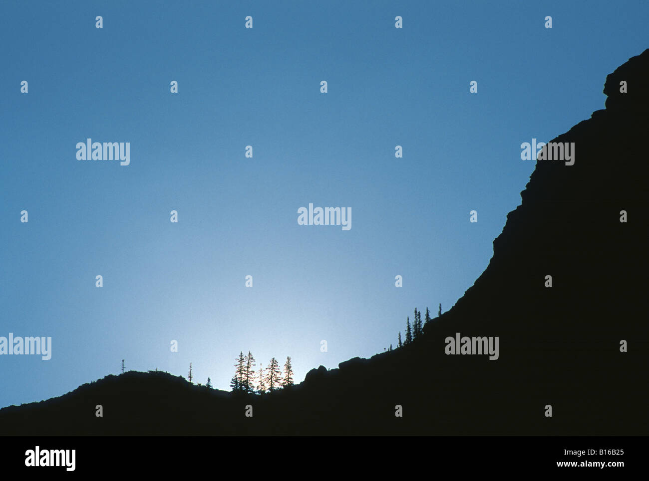 Rising sun silhouettes trees on the ridgeline outside Telluride ...