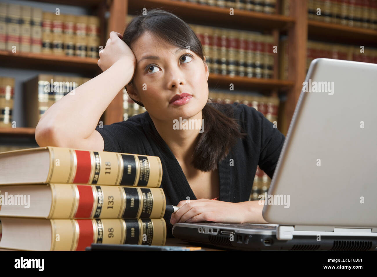 Asian woman leaning on stack of library books Stock Photo - Alamy