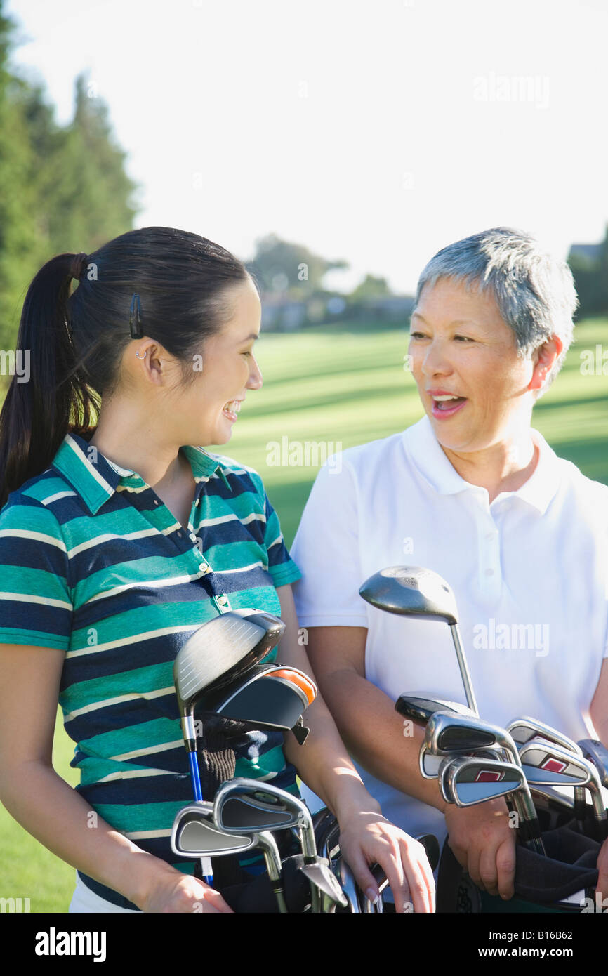 Asian mother and adult daughter holding golf bags Stock Photo - Alamy