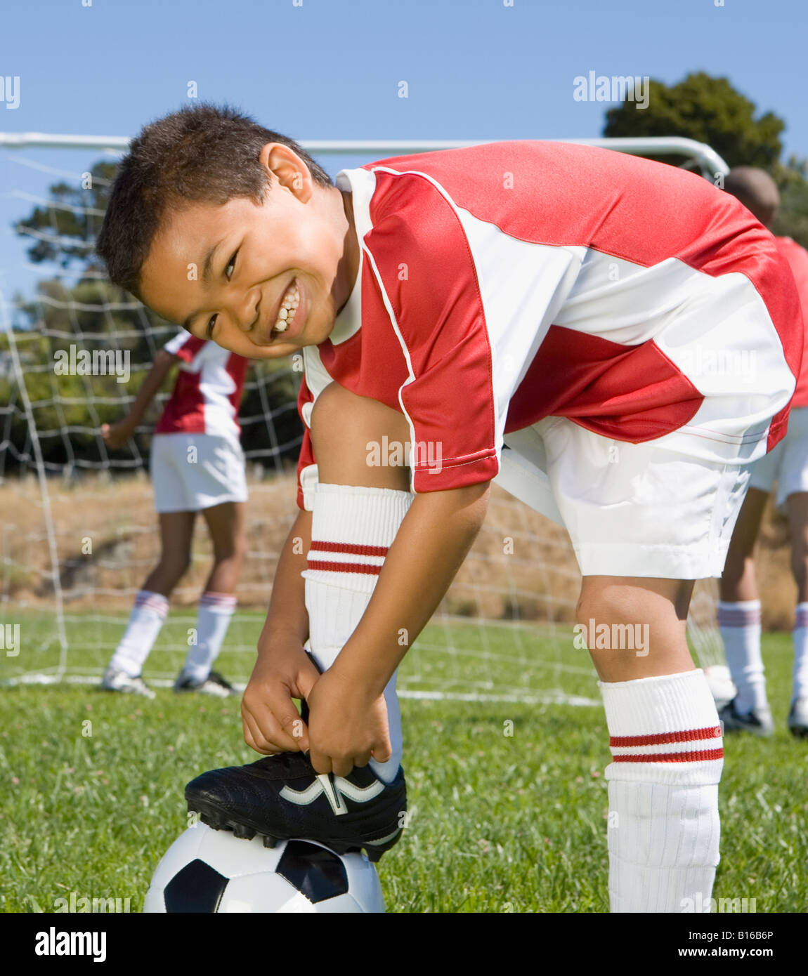 Mixed Race boy tying soccer shoe Stock Photo - Alamy
