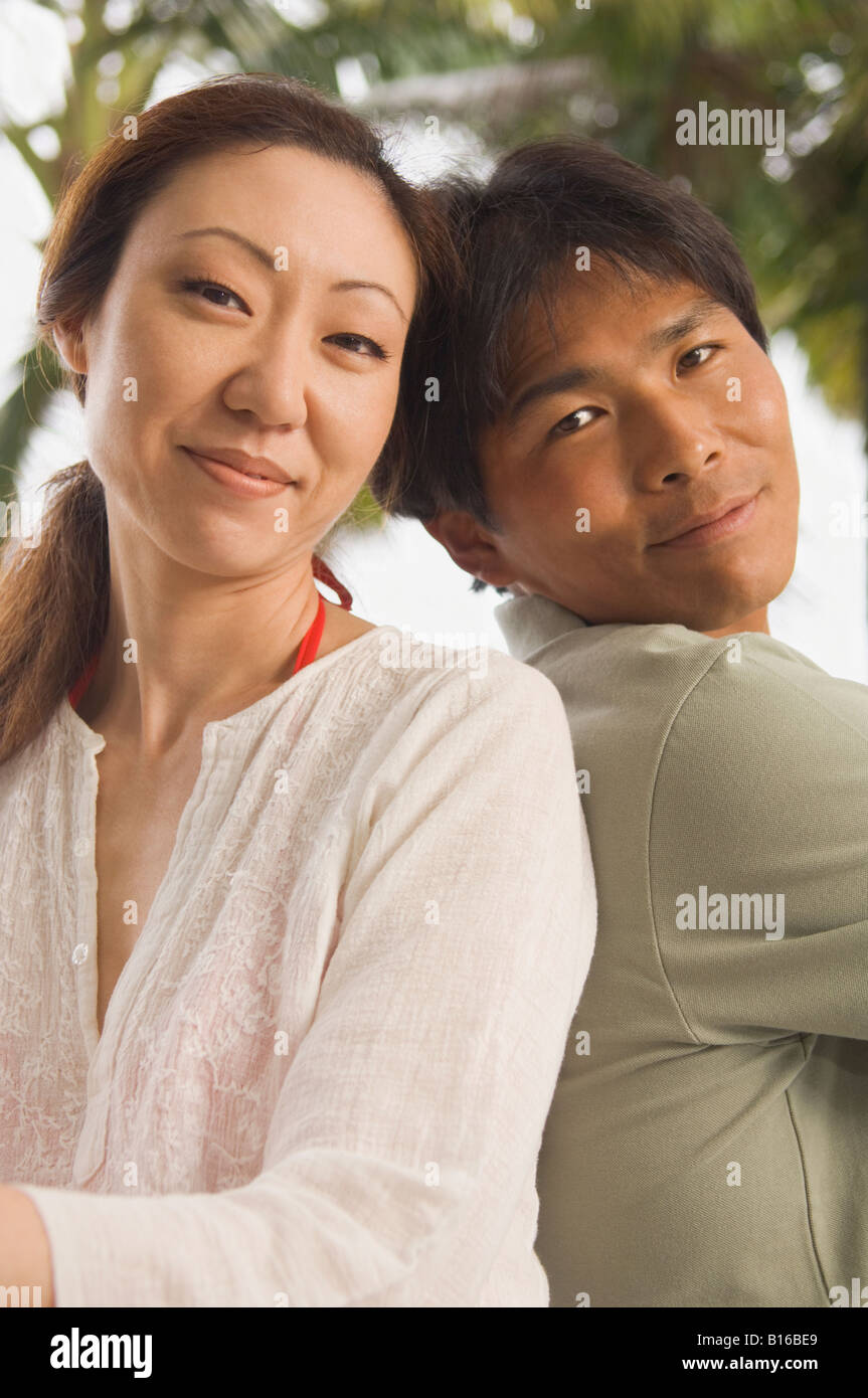 Asian couple sitting back to back Stock Photo - Alamy