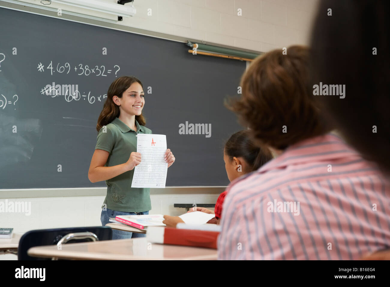 Girl holding paper in front of class Stock Photo - Alamy
