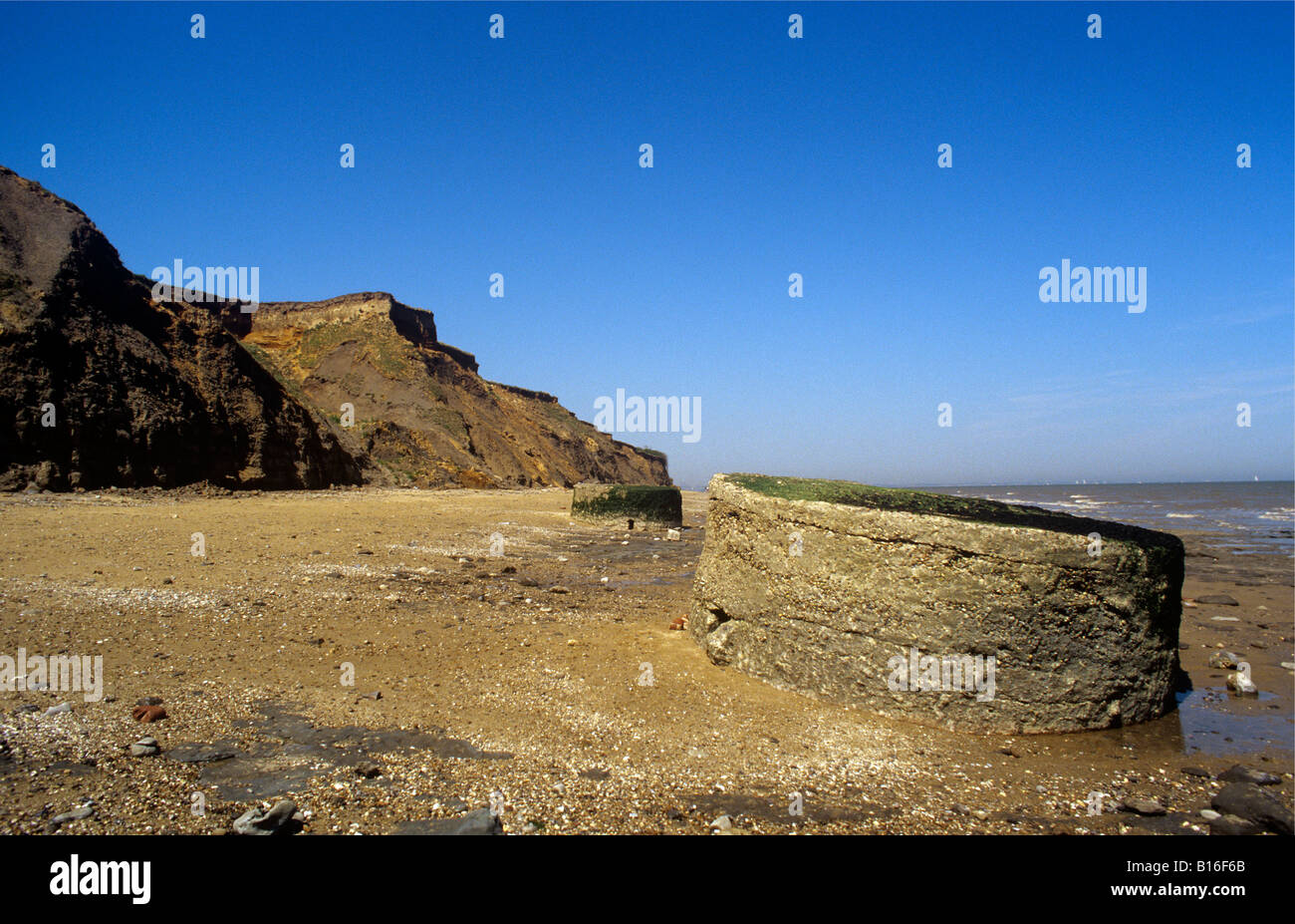Old concrete gun emplacements on the beach below receding cliffs west ...