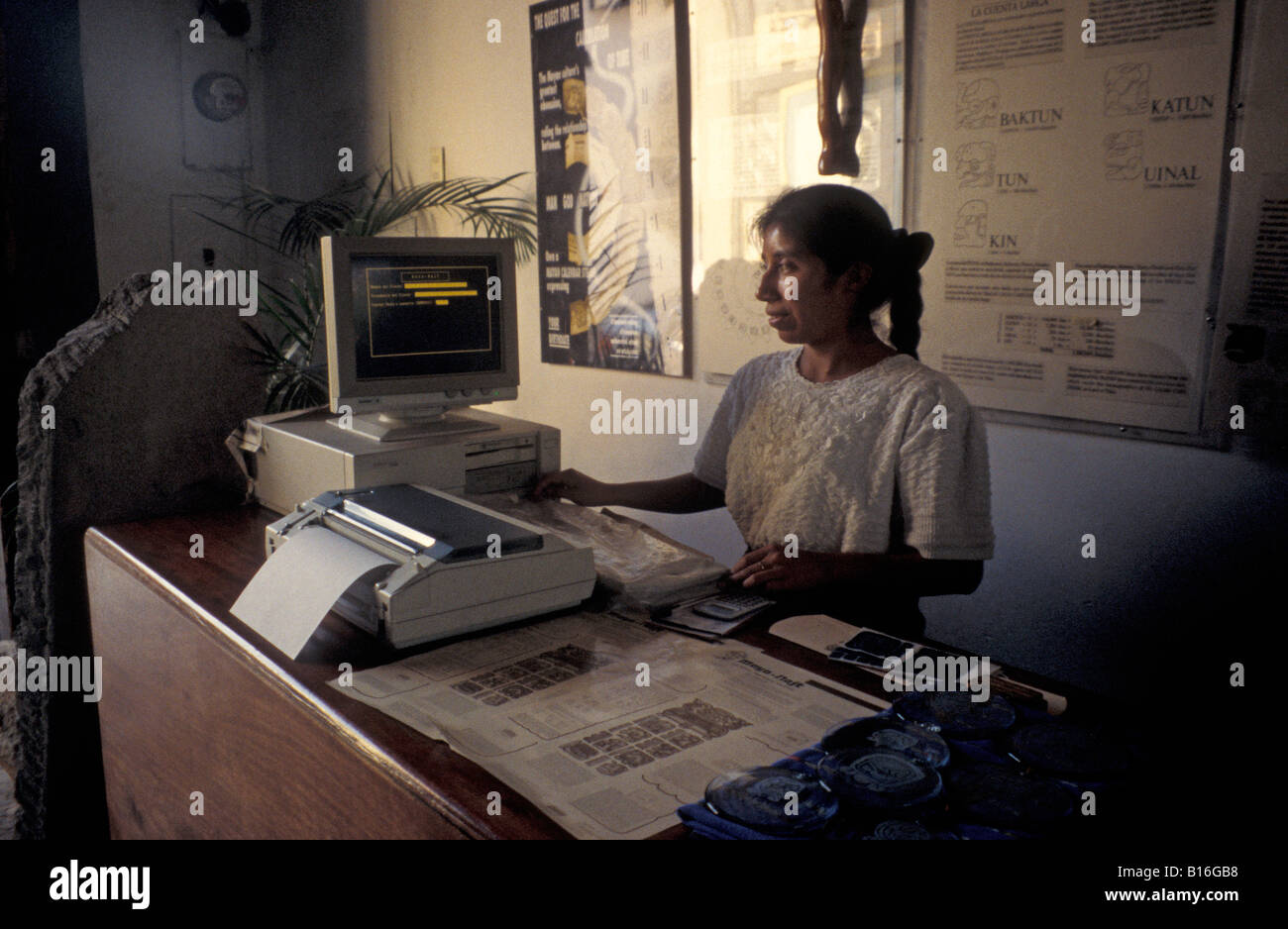 Young Maya woman sitting at a desk using a computer to prepare ...