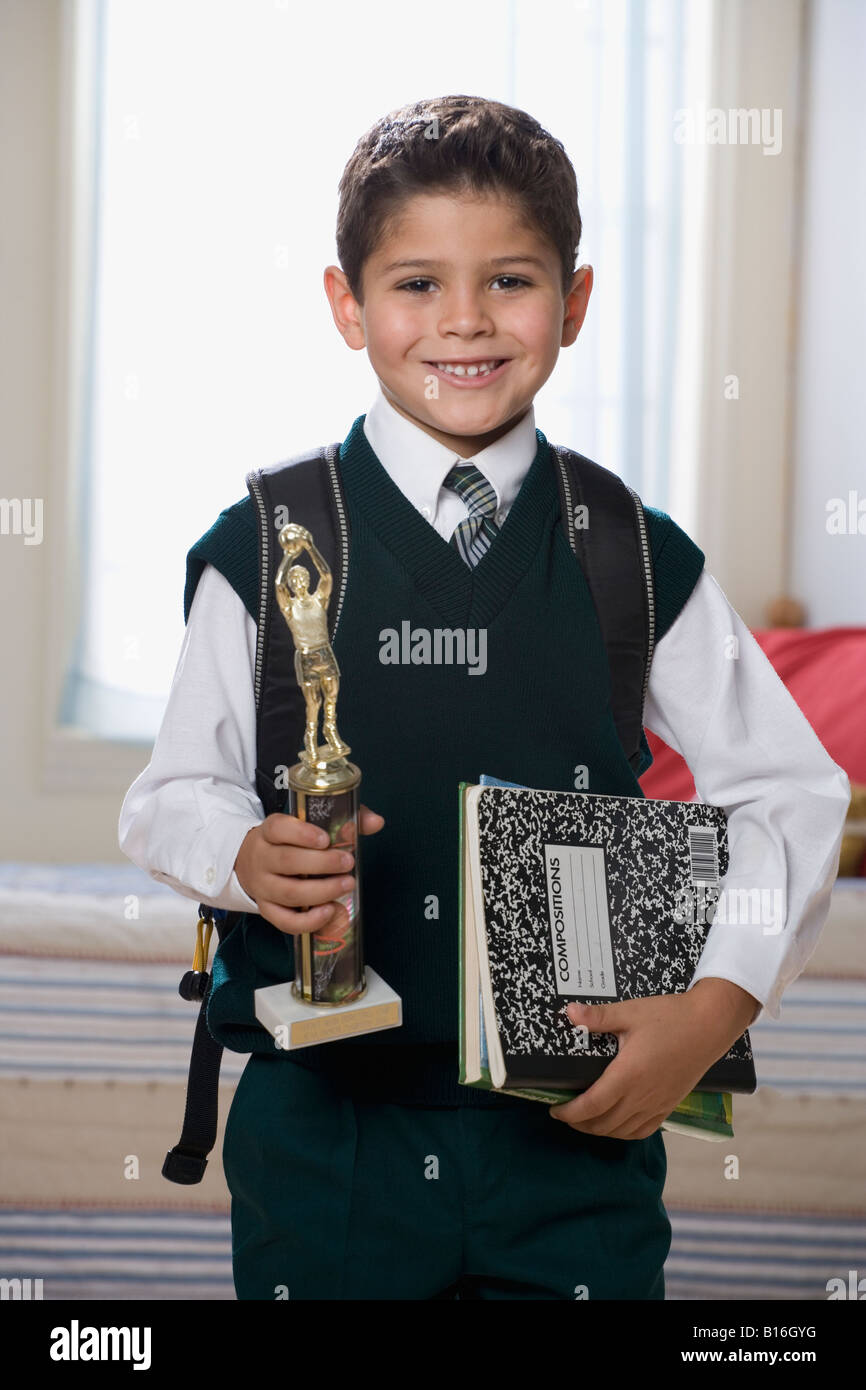Hispanic boy holding trophy and school books Stock Photo - Alamy