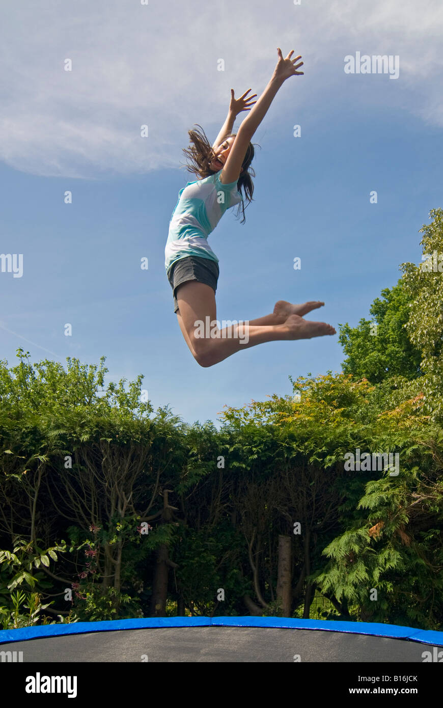 Vertical wide angle of a young teenage girl bouncing on a trampoline ...