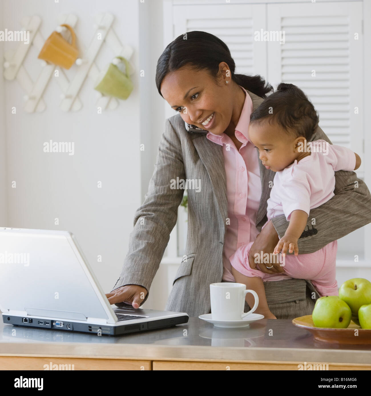 African American mother working at holding baby Stock Photo - Alamy