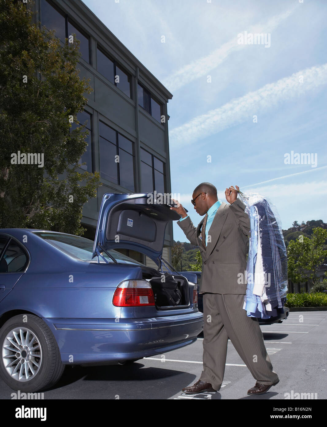 African businessman holding dry cleaning Stock Photo - Alamy