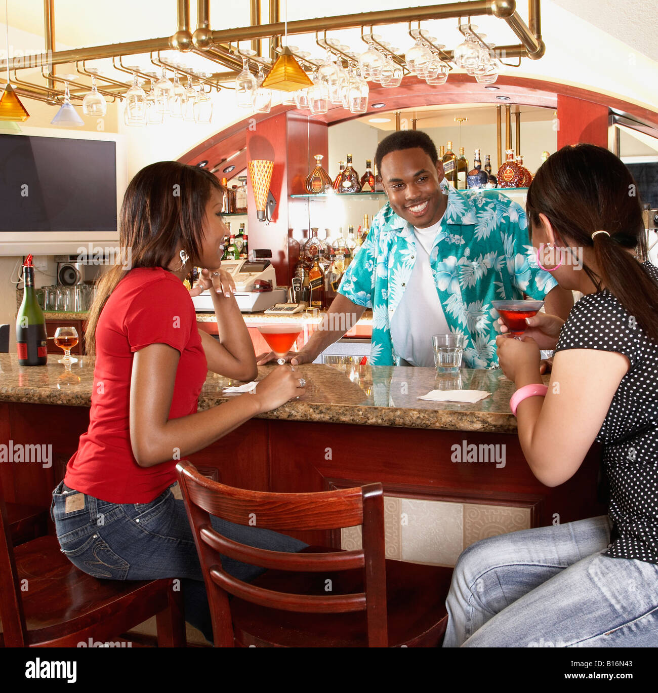 Multi-ethnic women sitting at bar Stock Photo - Alamy