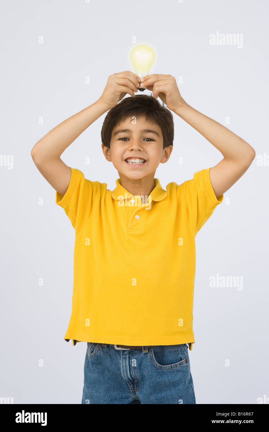 Middle Eastern boy holding light bulb over head Stock Photo - Alamy