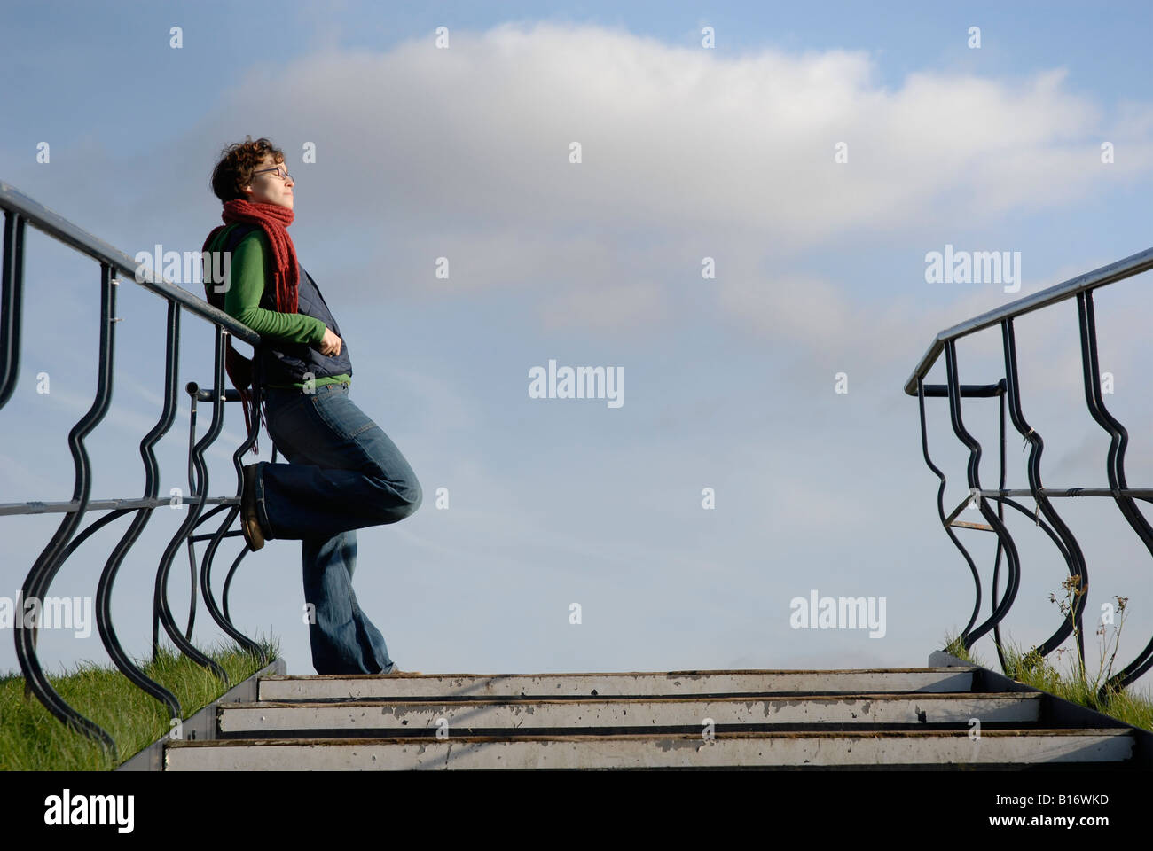Woman leaning against staircase railing, enjoying the sun Stock Photo ...
