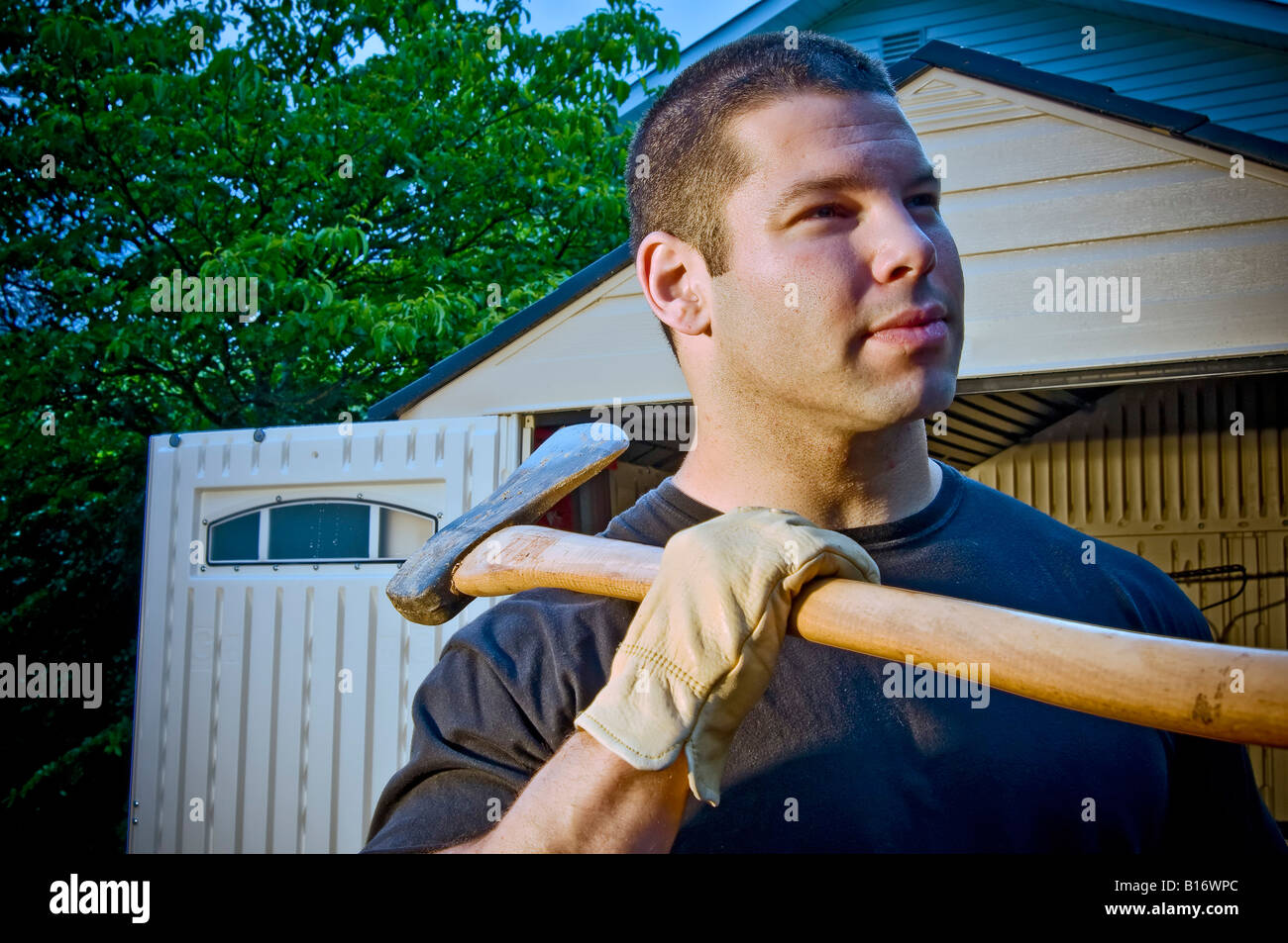 A muscular man holds an ax over his shoulder with a toolshed behind him ...