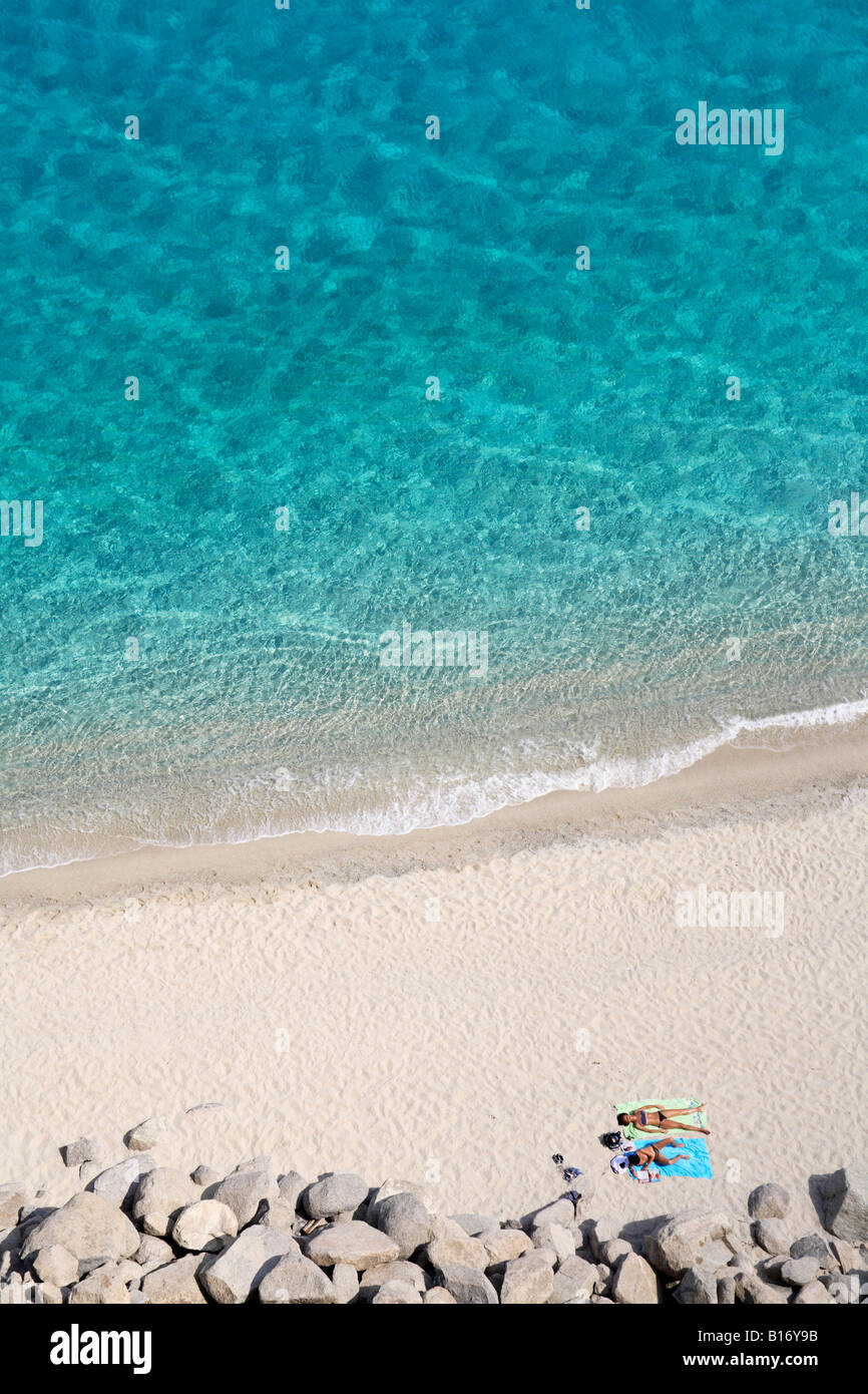 a birdseye view of two sunbathers lying on an empty beach in tropea ...