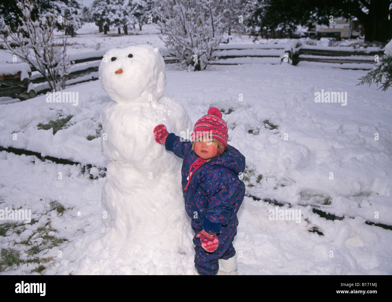 A young girl makes a snow man with a carrot nose during a heavy ...