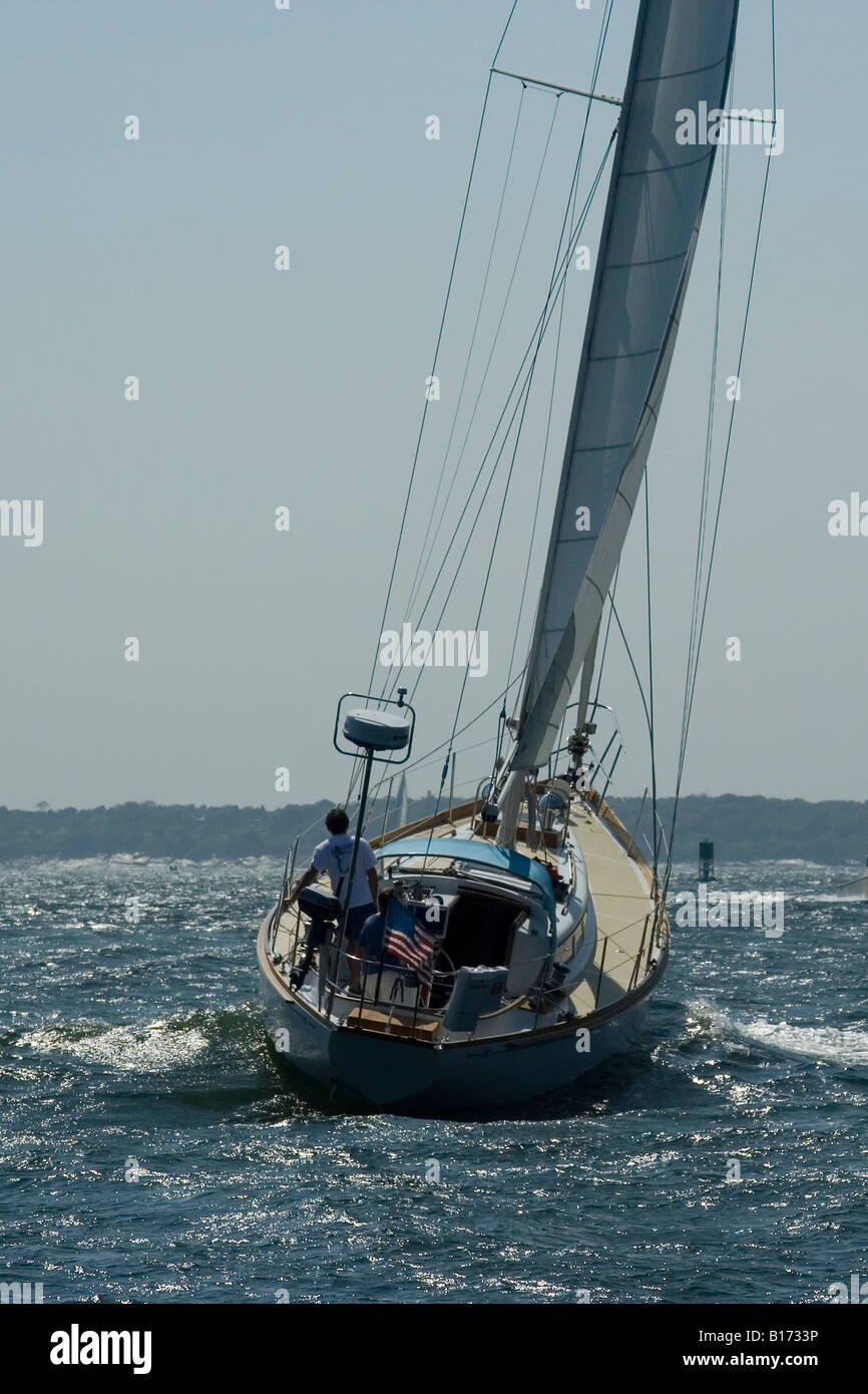 Photo of a classic sail boat sailing in open water with land in the ...