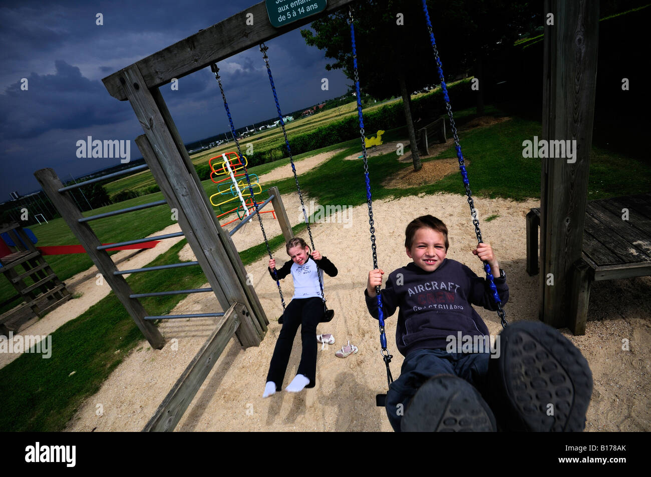Boy and girl on a swing teeter playground in move Stock Photo - Alamy