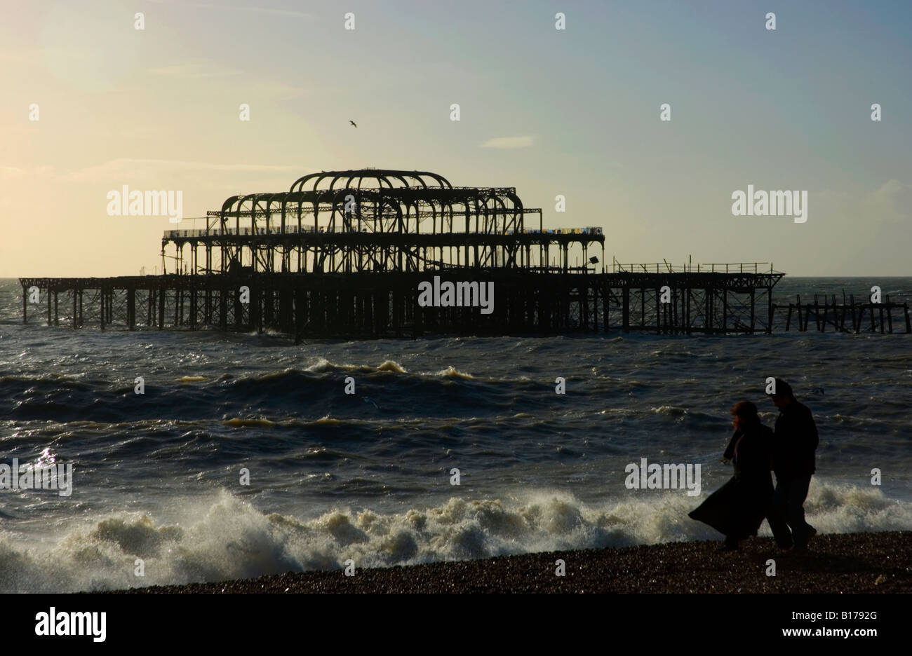 England Two people walk past the remains of the West Pier in Brighton ...