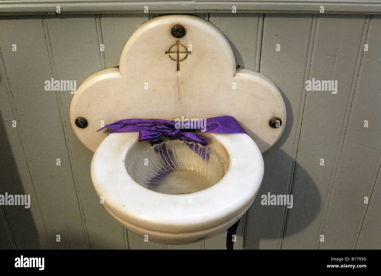 A holy water receptacle draped with a purple ribbon for Holy Week ...