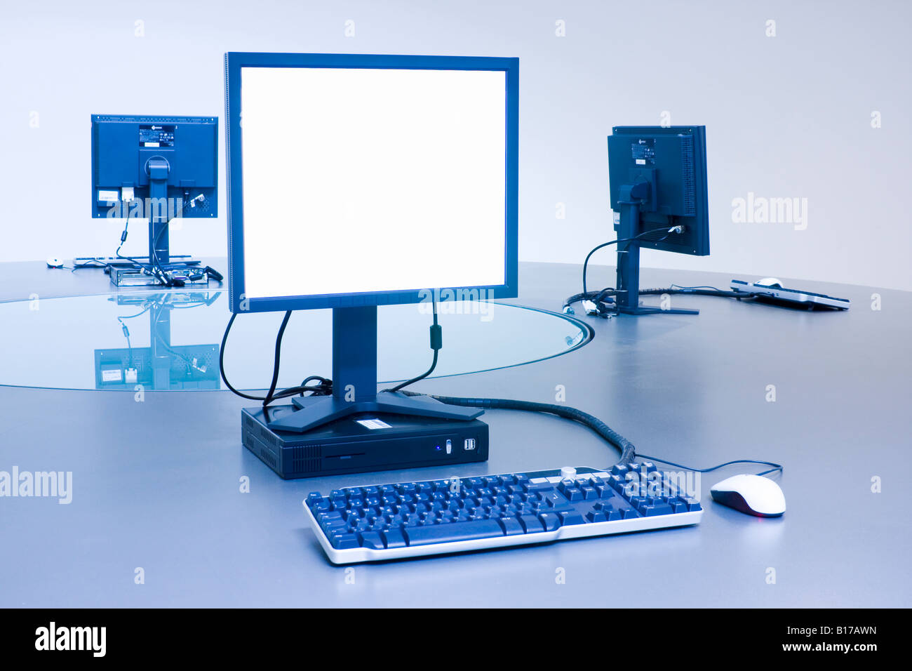 Three computers with keyboards on a big round table Stock Photo - Alamy