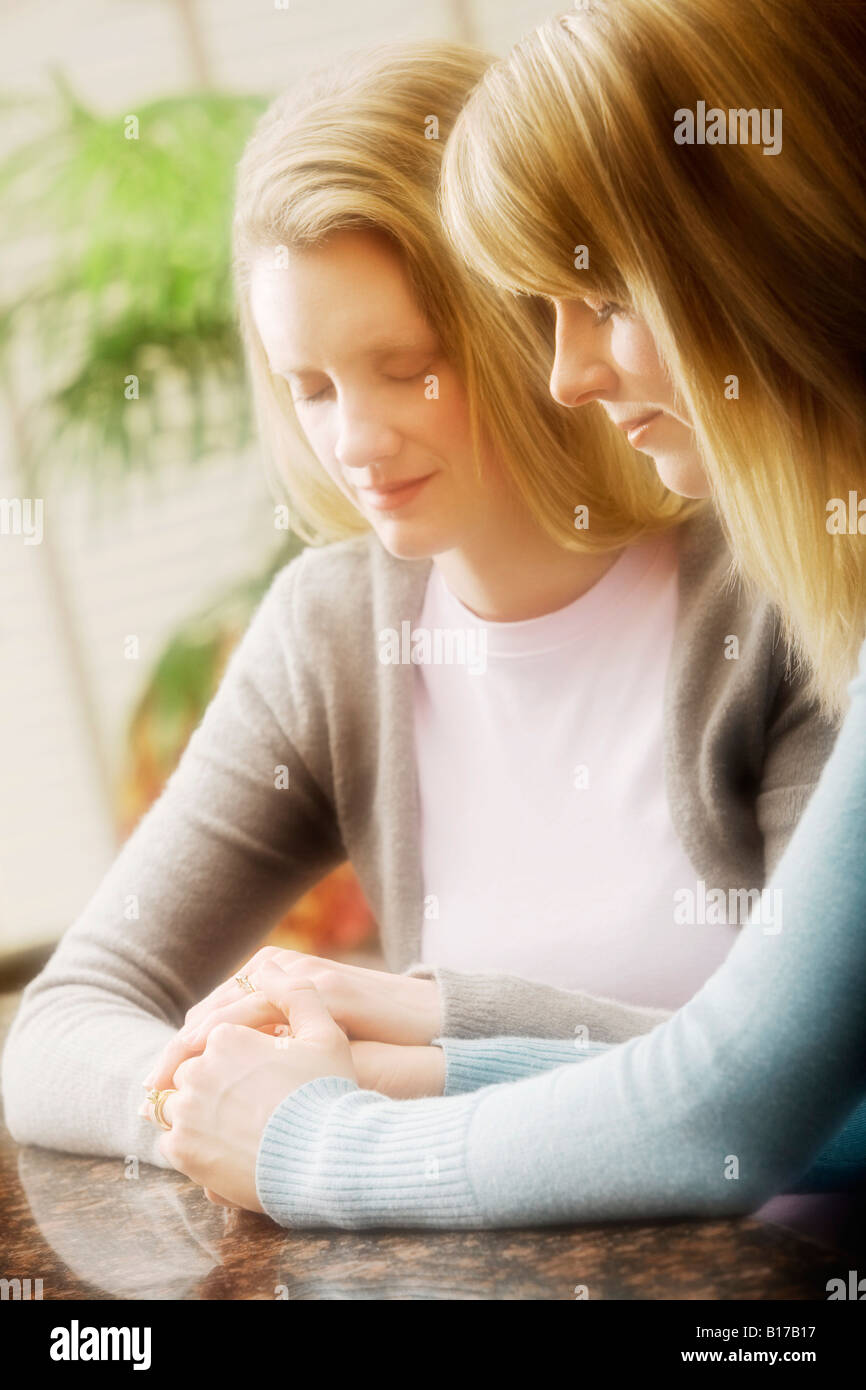 Two women praying together Stock Photo - Alamy